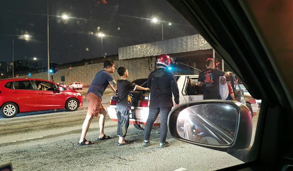 M’sians band together near traffic light junction to help push a broken ...